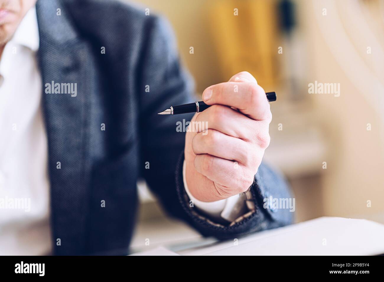 A lawyer, notary public signs an important document. Pen in his hand ...