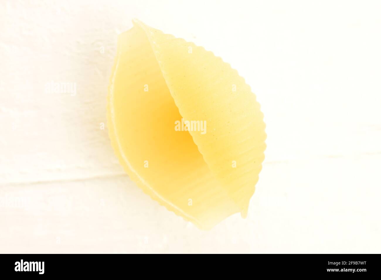 One slice bright yellow, organic, shell-shaped paste, on a painted ...