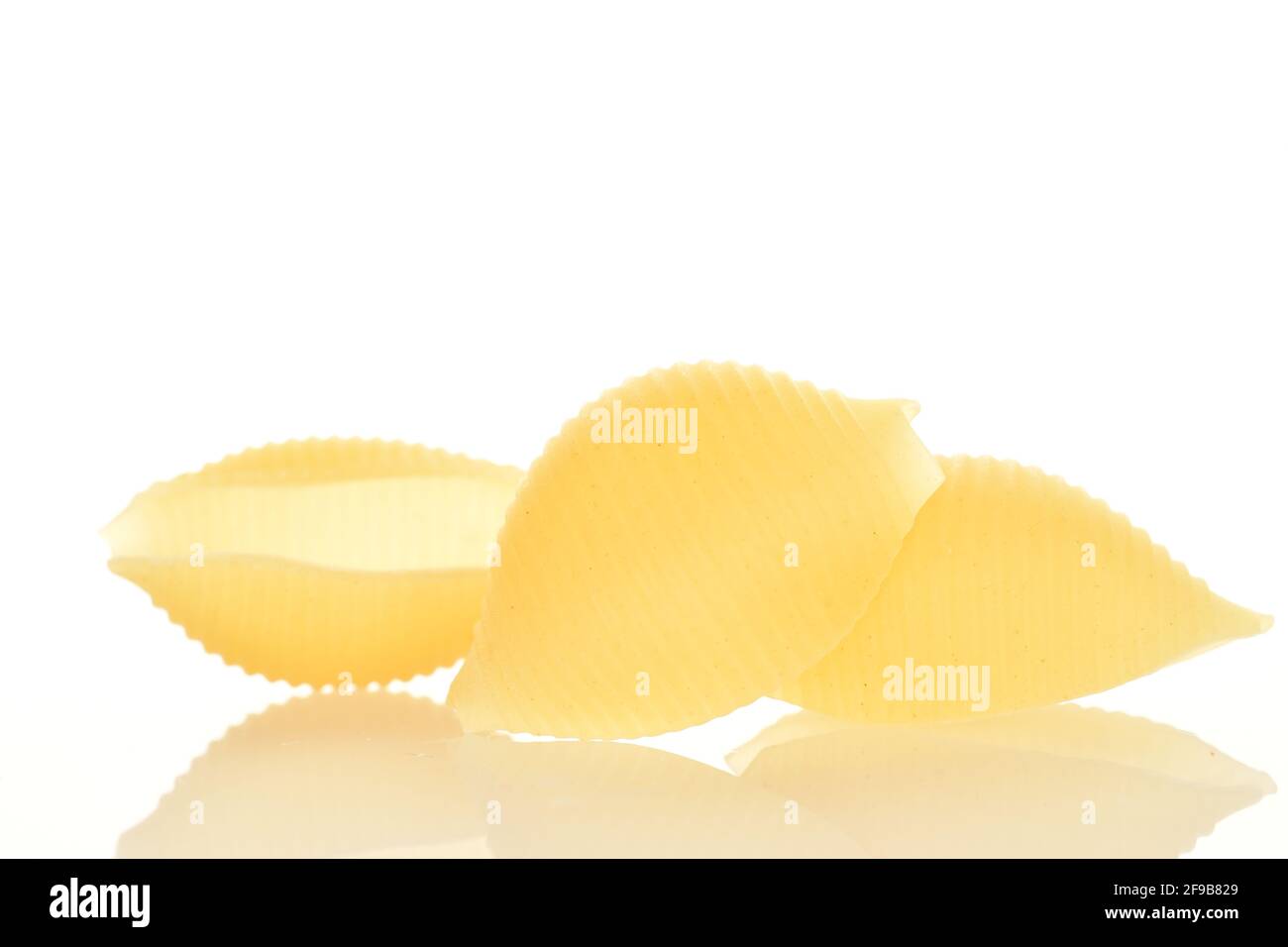 A few bright yellow, organic, not cooked pasta on a white background ...