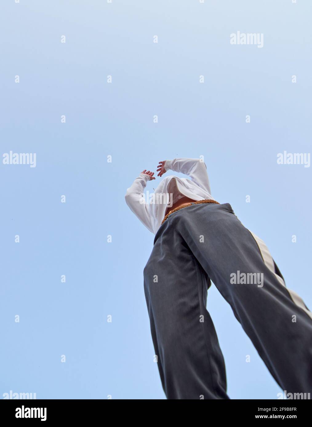 Vertical low angle shot of a young male reaching up on a windy day ...