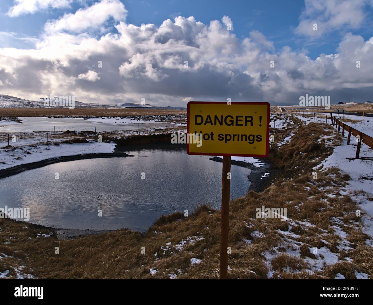 Yellow colored warning sign (danger) in front of hot springs at ...