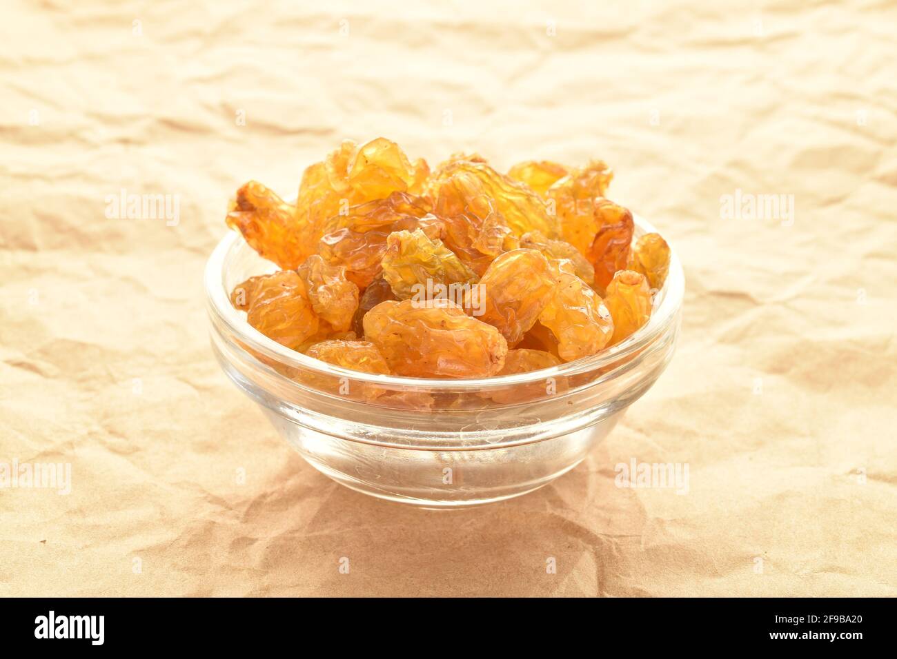 Yellow-golden organic raisins in glassware, close-up, on craft paper ...