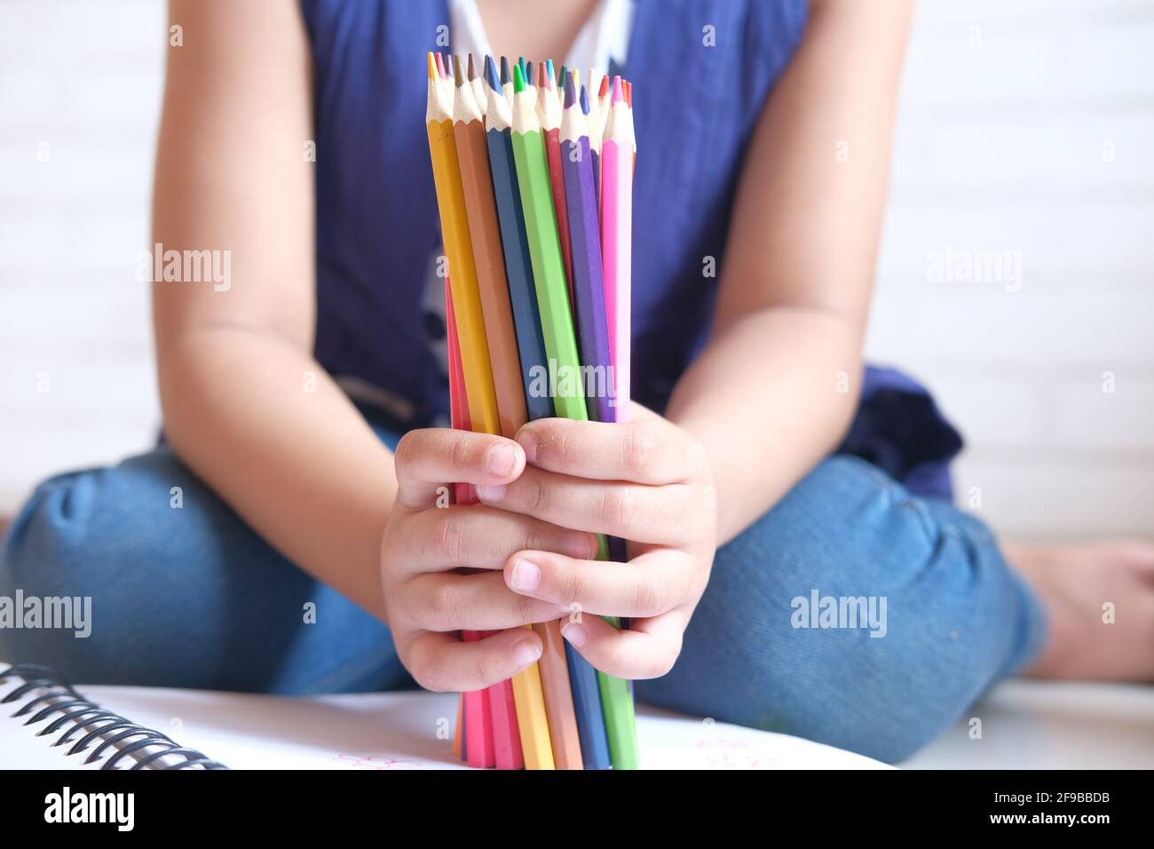 child girl holding many color pencils sitting on floor Stock Photo - Alamy