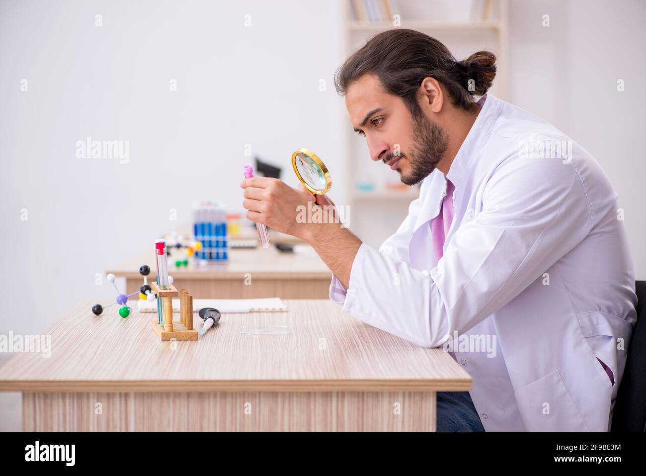 Young chemist sitting at the desk in the classroom Stock Photo - Alamy