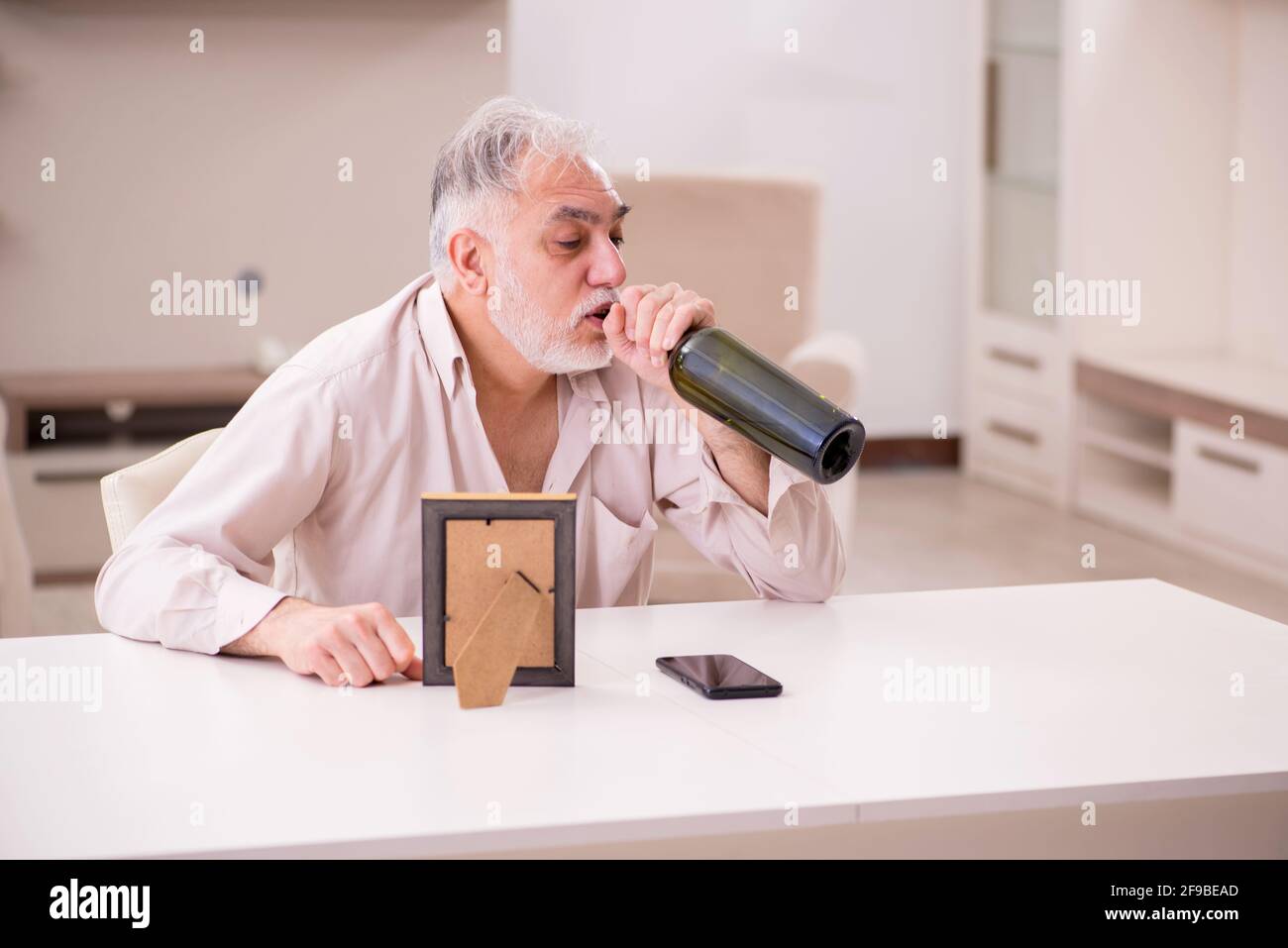 Aged widower drinking alcohol at home Stock Photo - Alamy