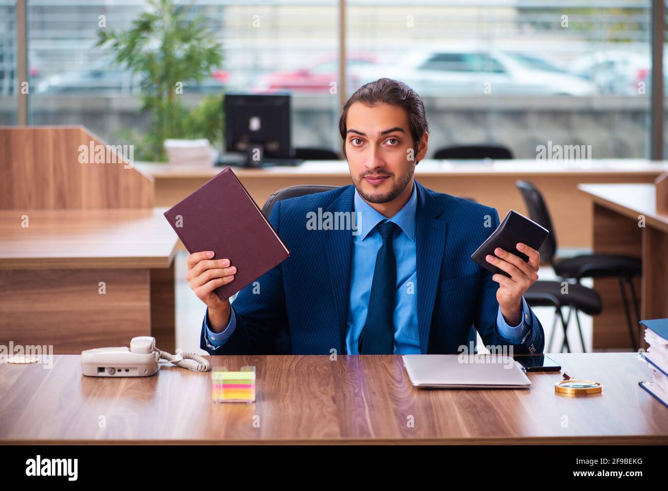 Young employee reading book in the office Stock Photo - Alamy