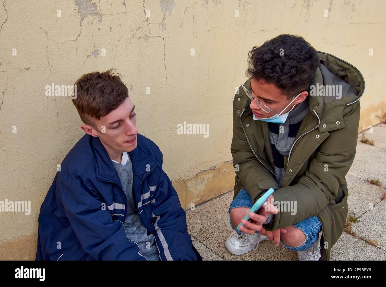 Young male showing photos from his phone to his friend Stock Photo - Alamy