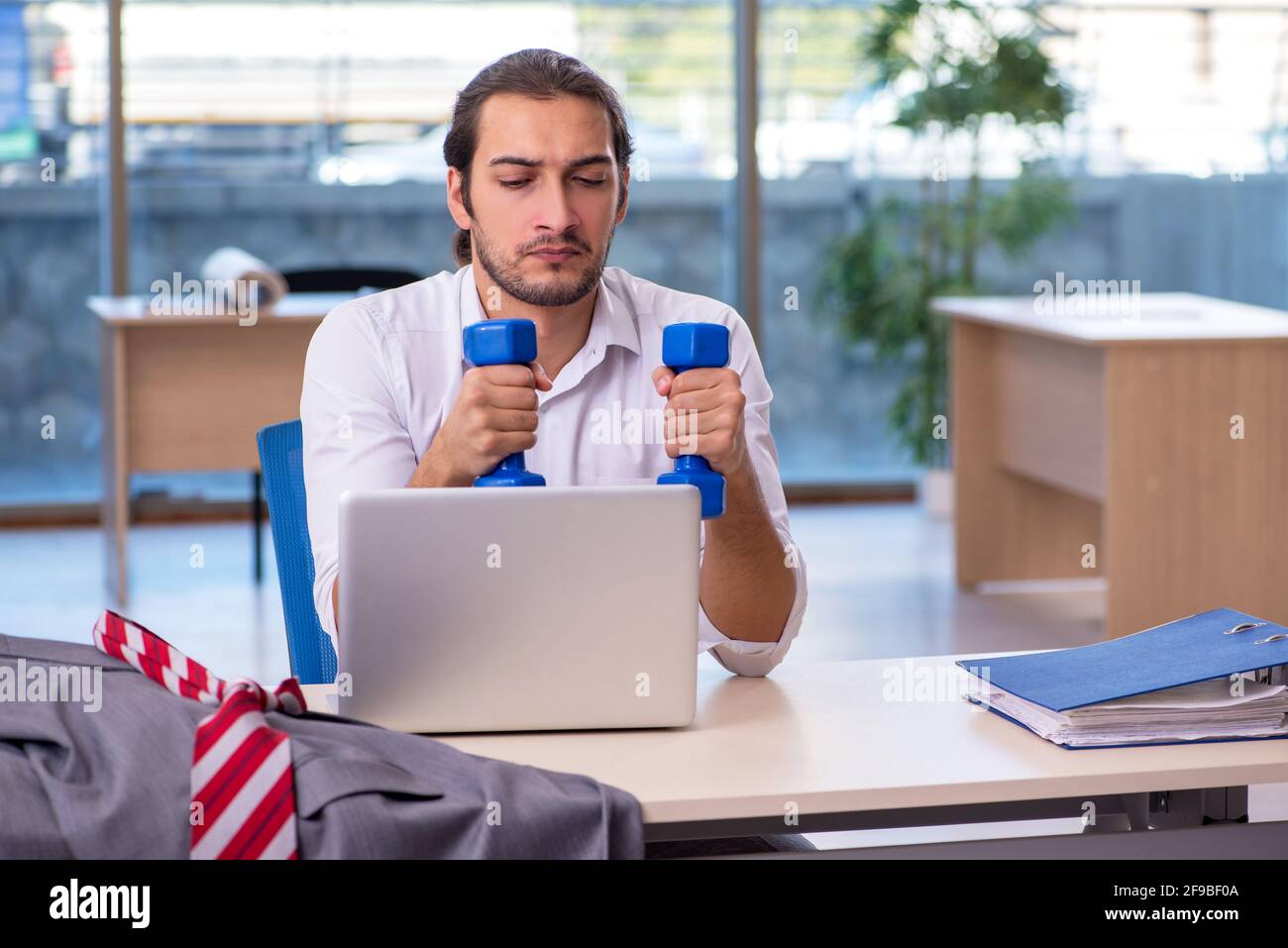 Young employee doing sport exercises at workplace Stock Photo - Alamy