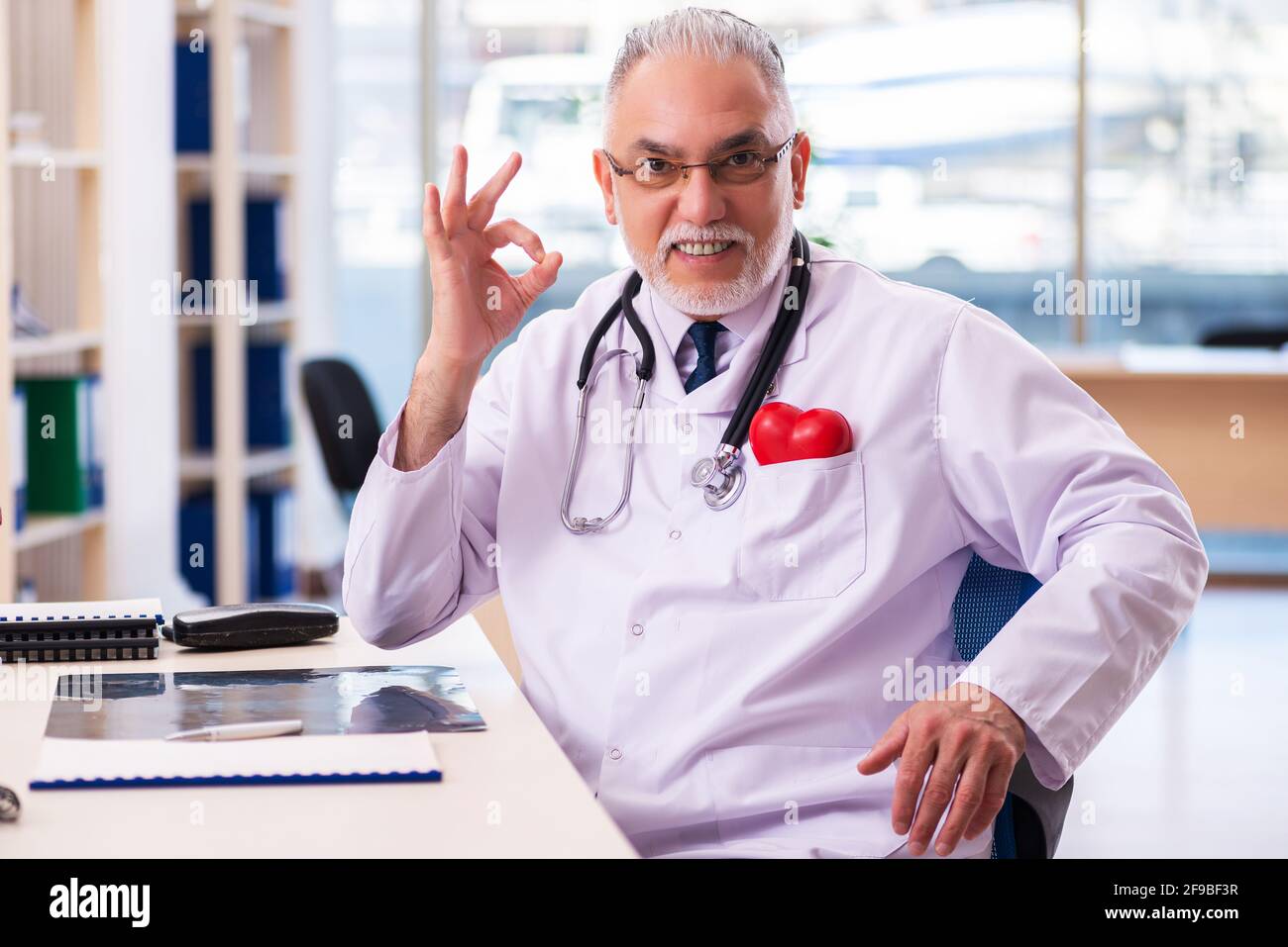 Old doctor cardiologist working in the clinic Stock Photo - Alamy