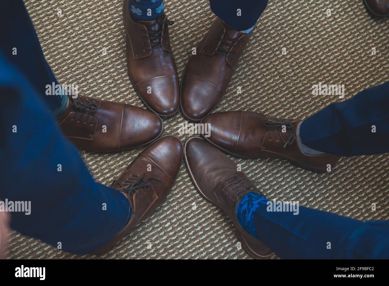 Closeup shot of males putting their feet in a circle with formal shoes ...
