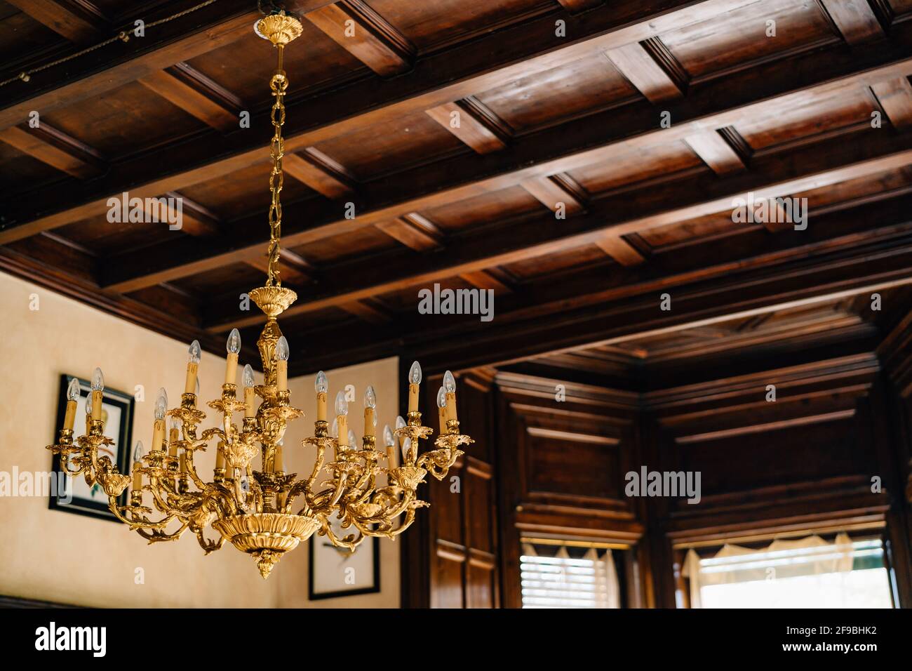Gold chandelier on a chain under a wooden ceiling Stock Photo - Alamy