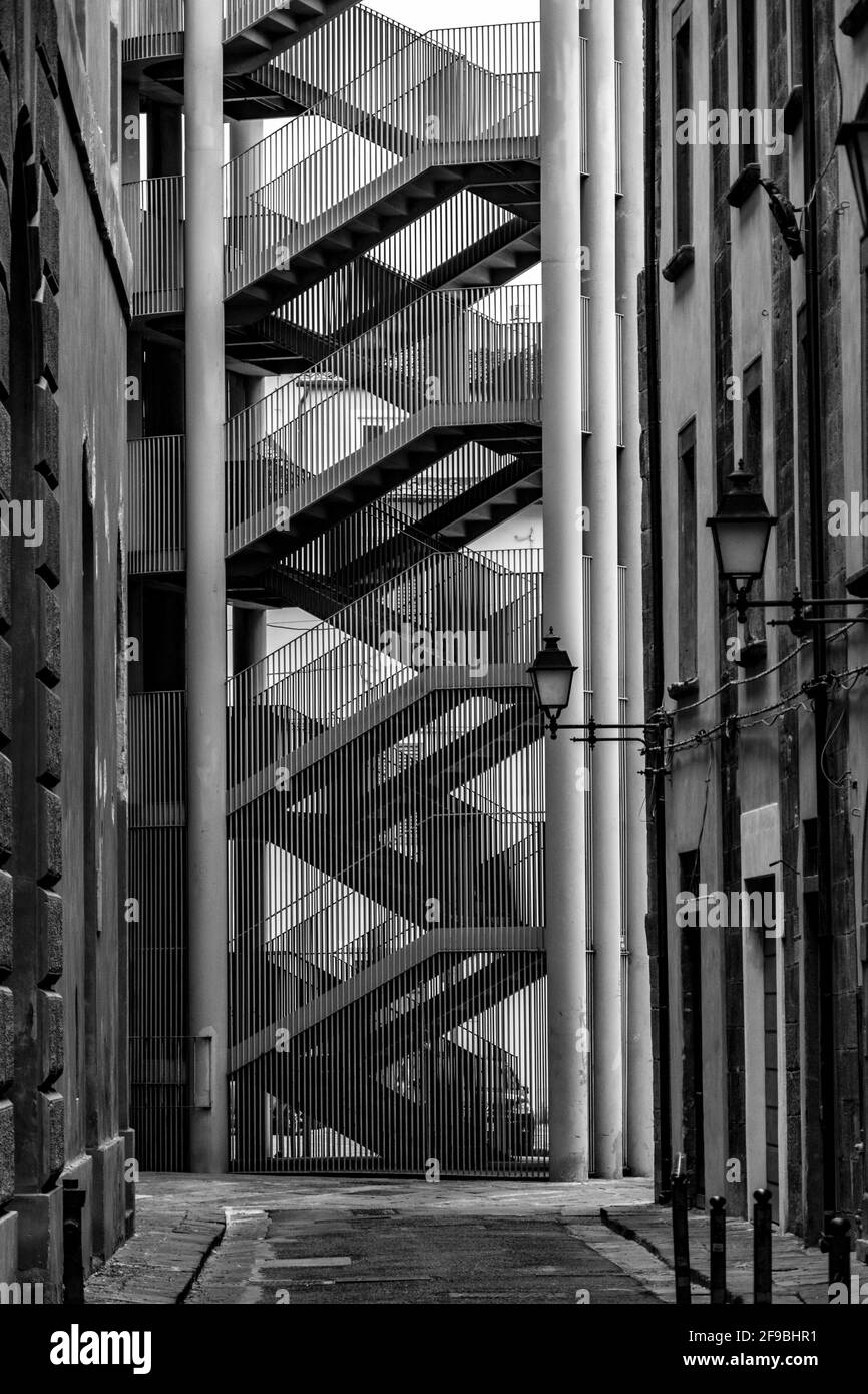 Vertical grayscale shot of alleyway with escalators background in Pisa ...
