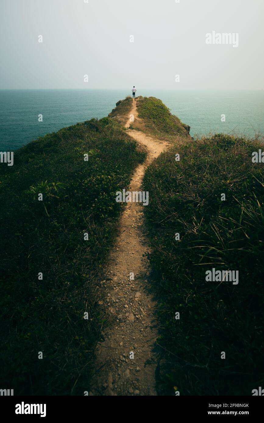 Vertical shot of a narrow walkway on the cliff peak leading to the edge ...