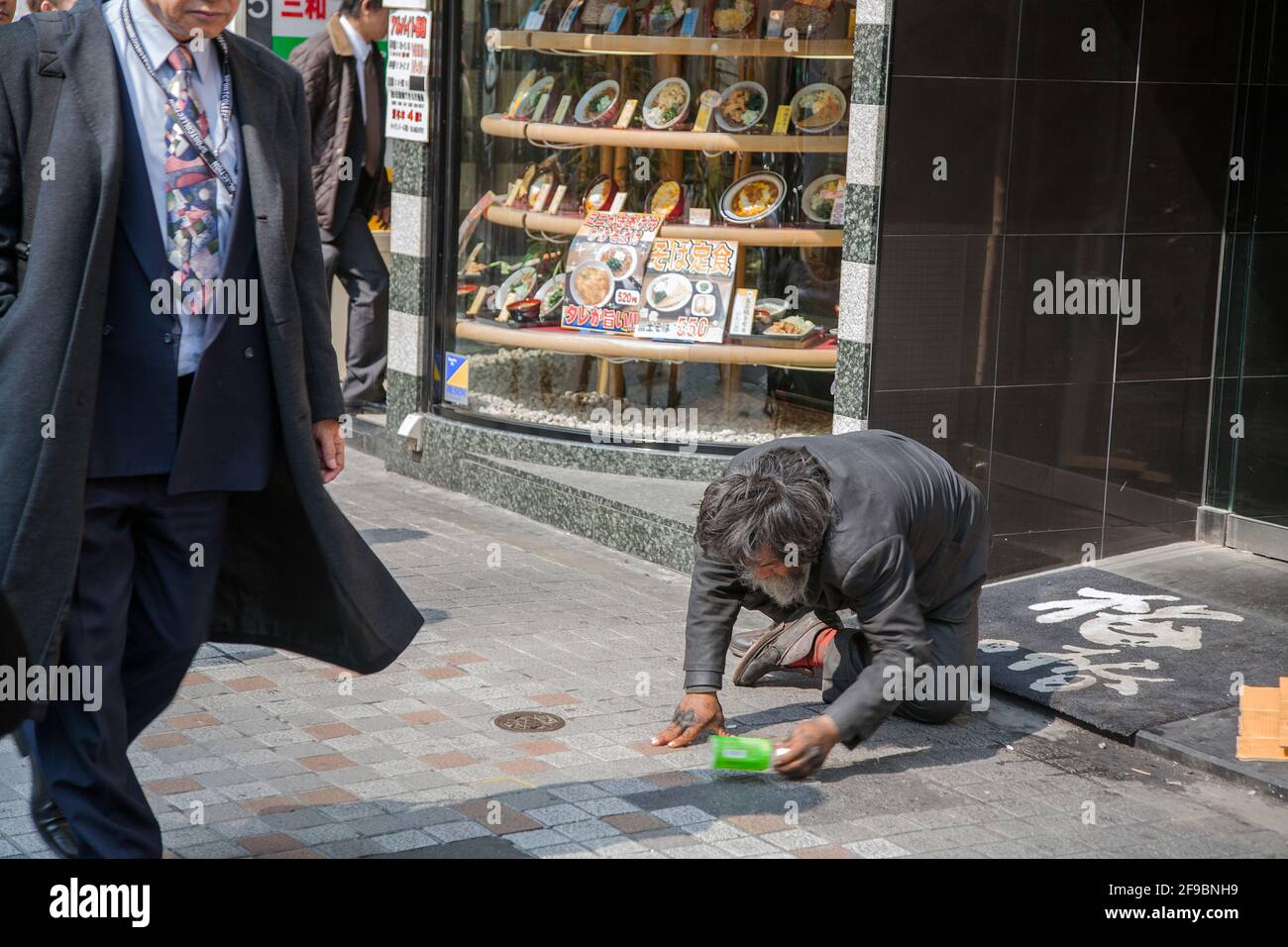 Homeless Japanese male on street beside restaurant displaying plastic ...
