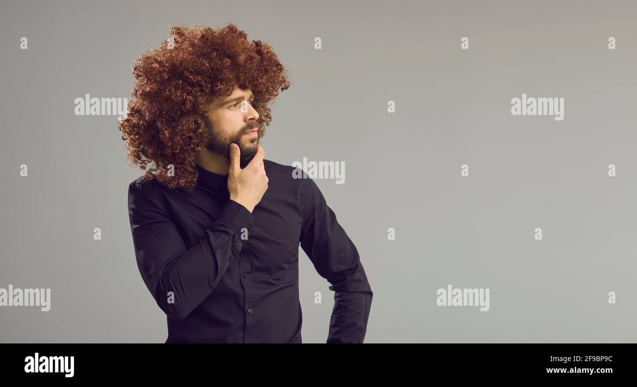 Funny intrigued man looking away at copy space standing on grey banner ...