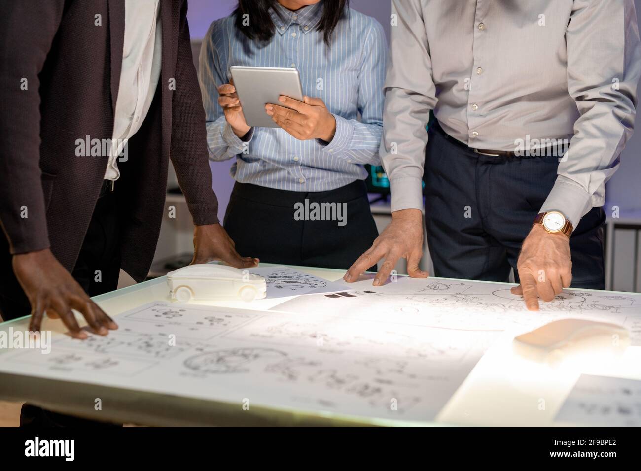 Cropped image of multi-ethnic colleagues standing at table and creating ...