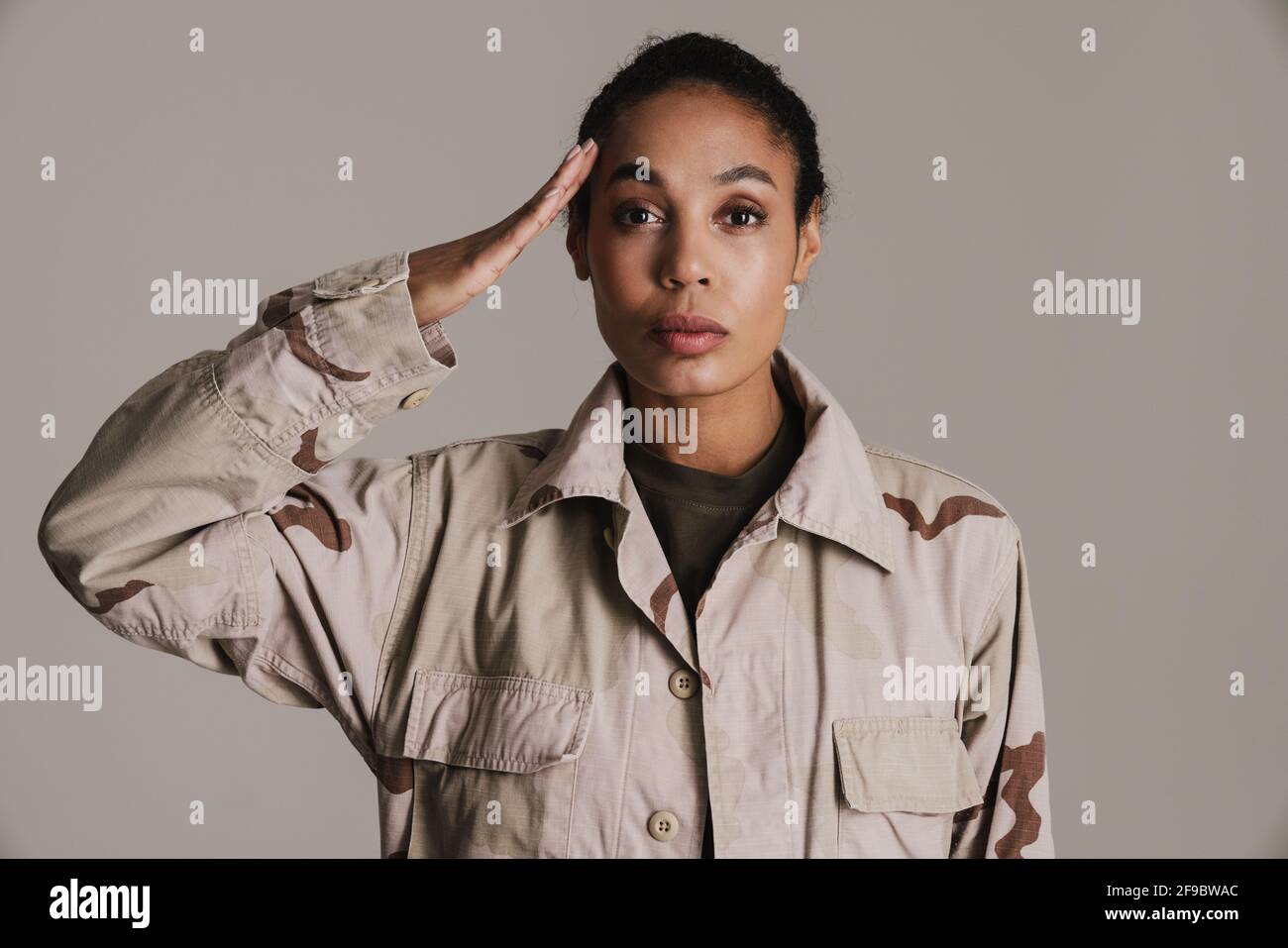 Confident african american soldier woman posing and saluting isolated ...