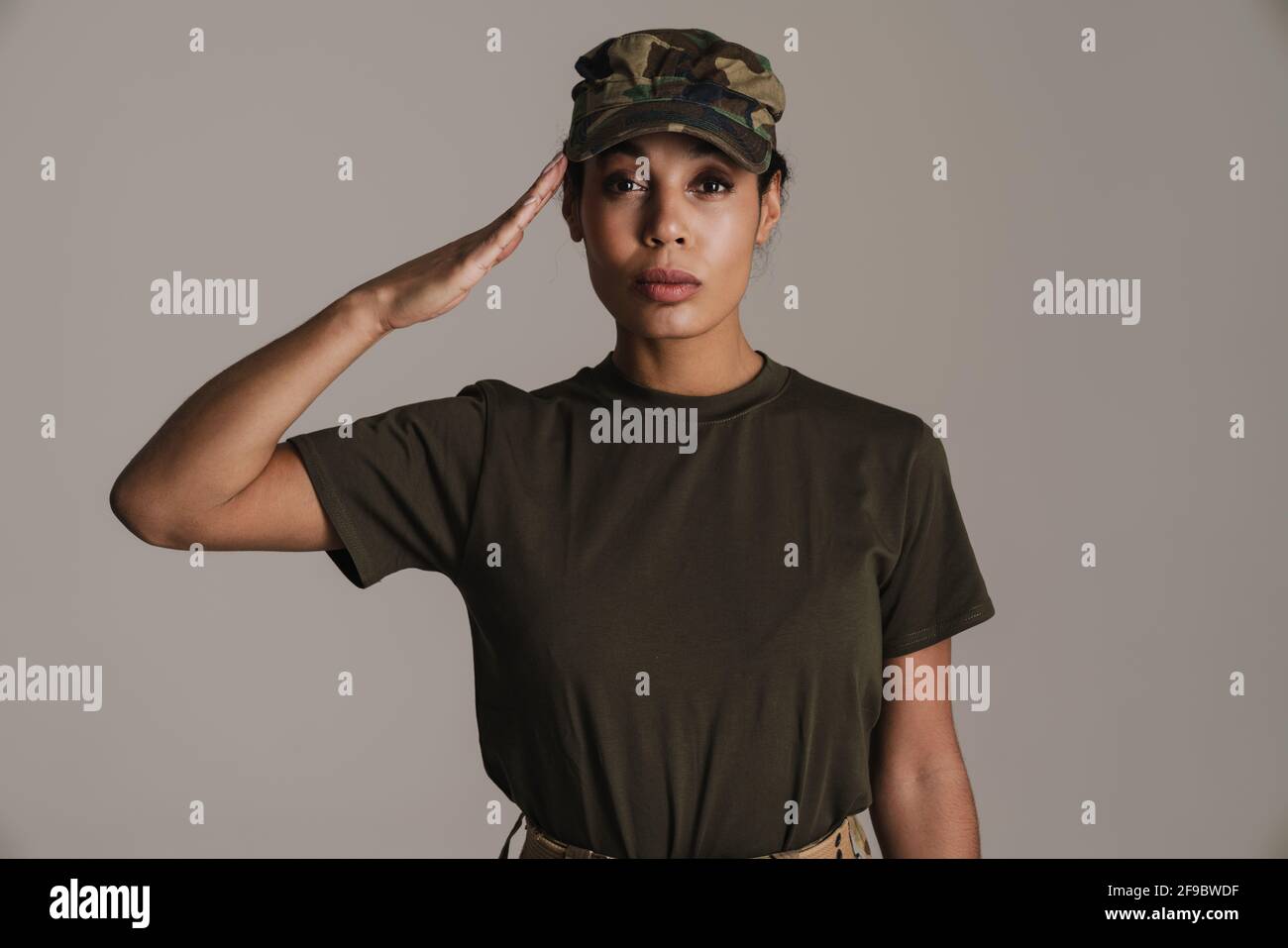 Confident african american soldier woman saluting and looking at camera ...