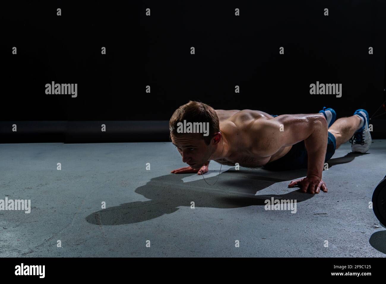 Man on black background keeps dumbbells pumped up in fitness active ...