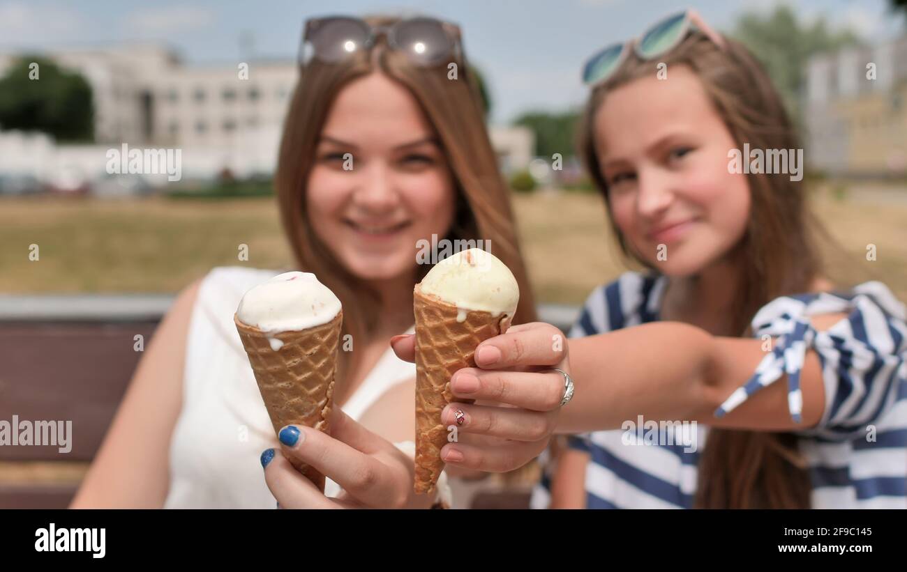 Two girls are presenting ice cream to the viewer Stock Photo - Alamy