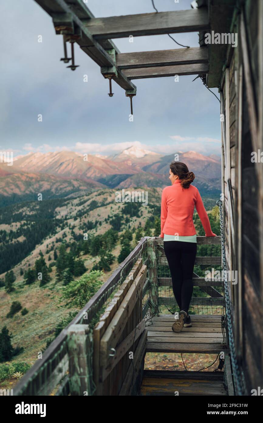 Young adventurer watching sunrise on top of fire lookout in Washington ...