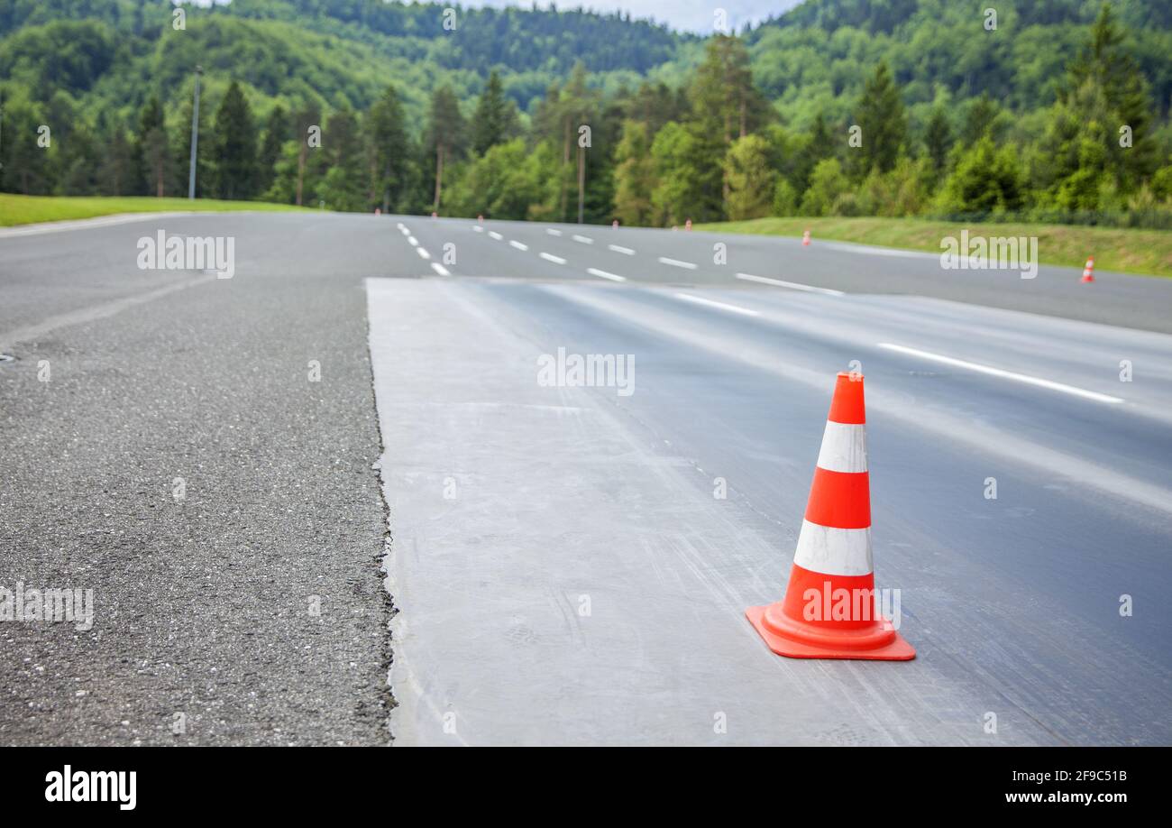Traffic cone on asphalt road with trees background Stock Photo - Alamy