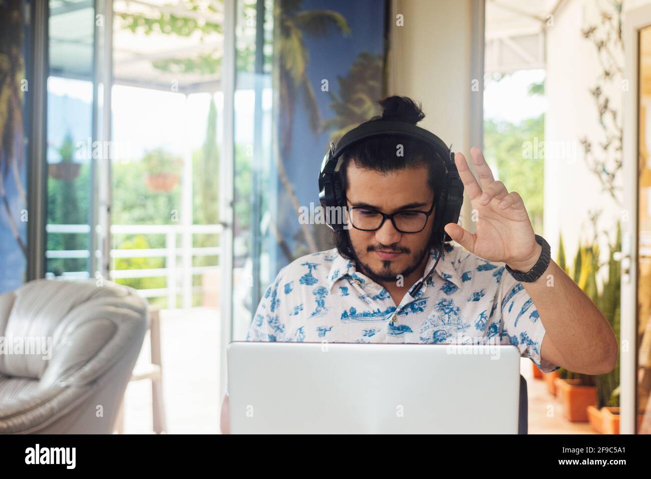 View of a Hispanic man waving hello to the camera while having a video ...
