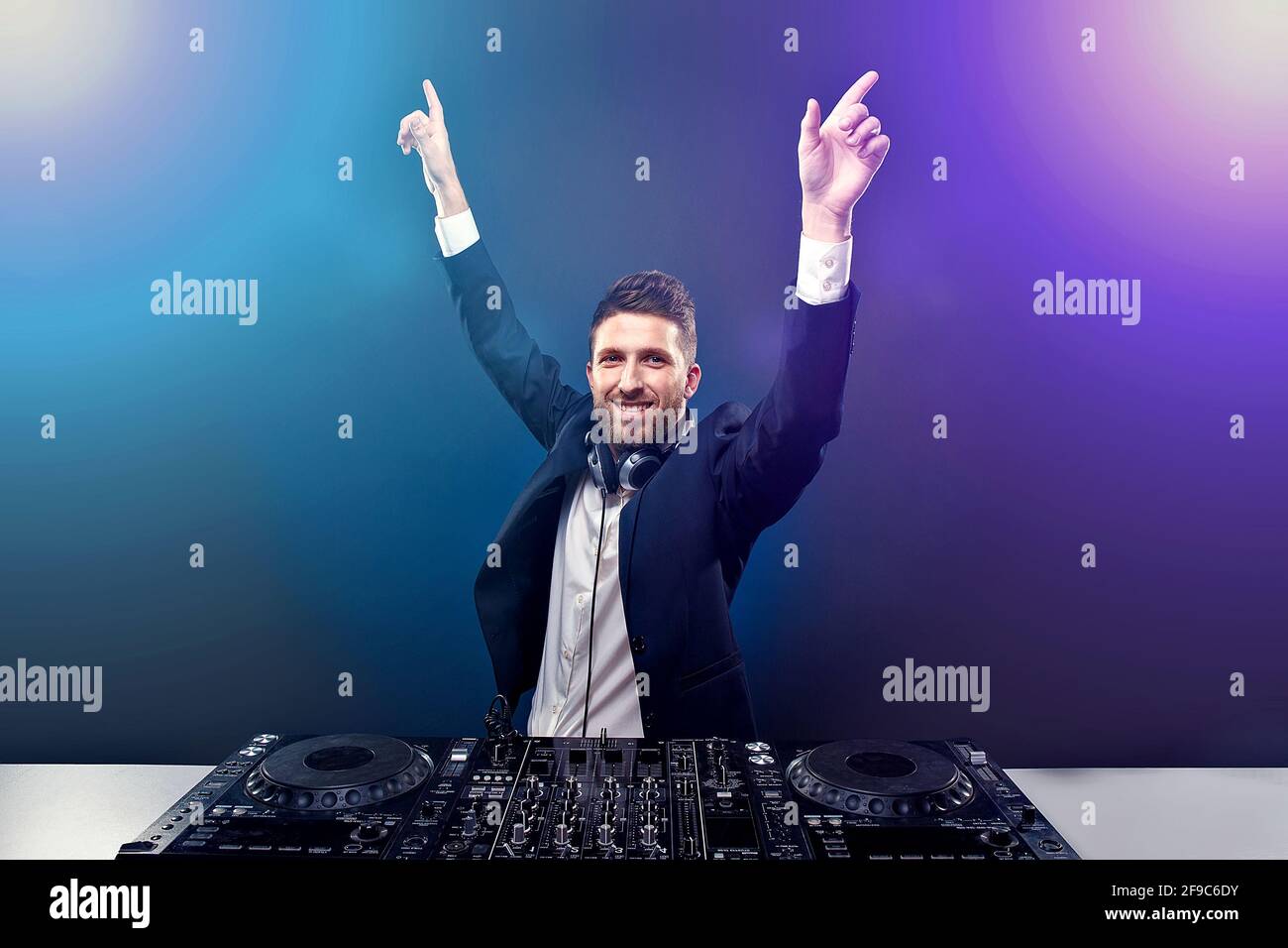 Man DJ in dark suit play music on a Dj's mixer. Studio shot. Dark blue ...