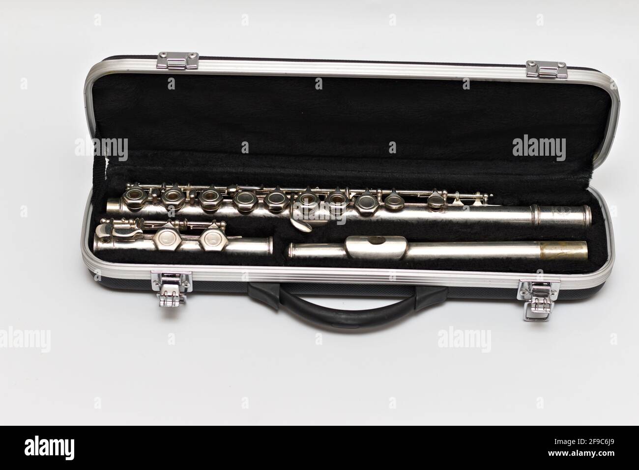 Partial view of a shiny disassembled silver flute in a black case ...