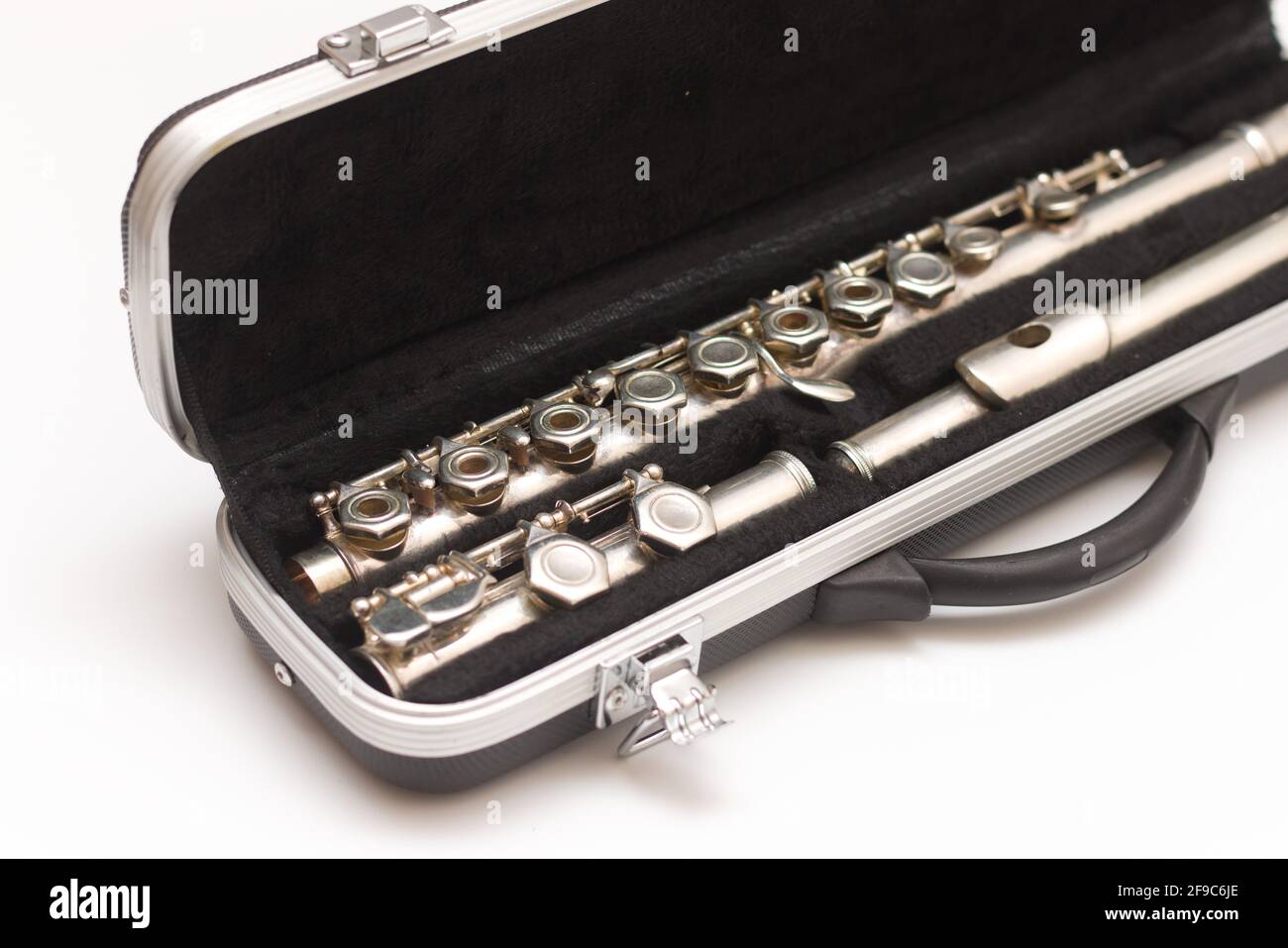 Partial side view of shiny disassembled silver flute in black case ...