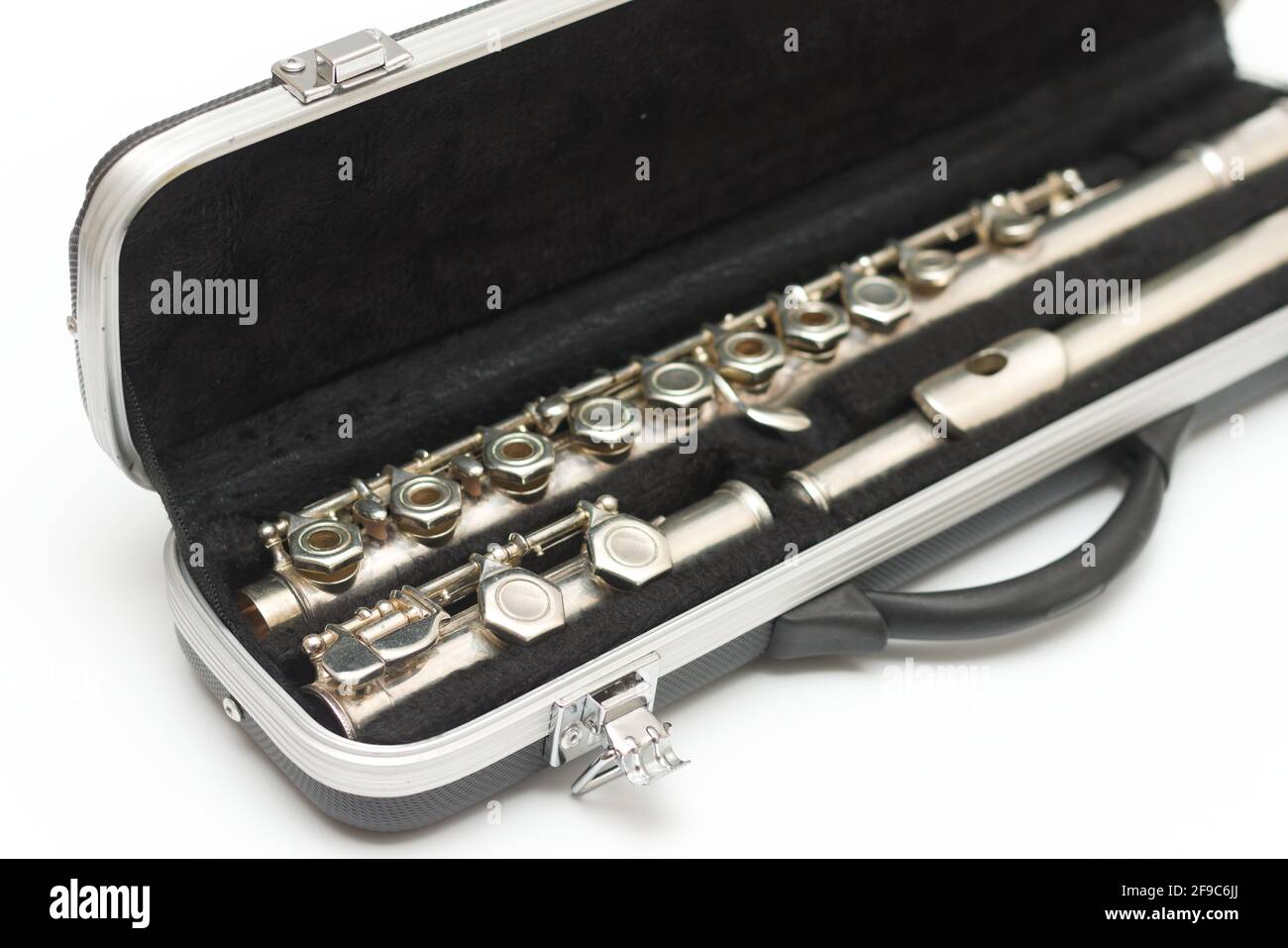 Partial side view of shiny disassembled silver flute in black case ...