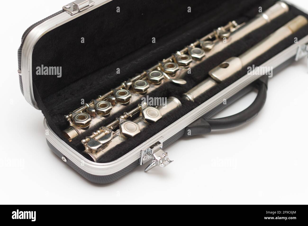 Partial side view of shiny disassembled silver flute in black case ...