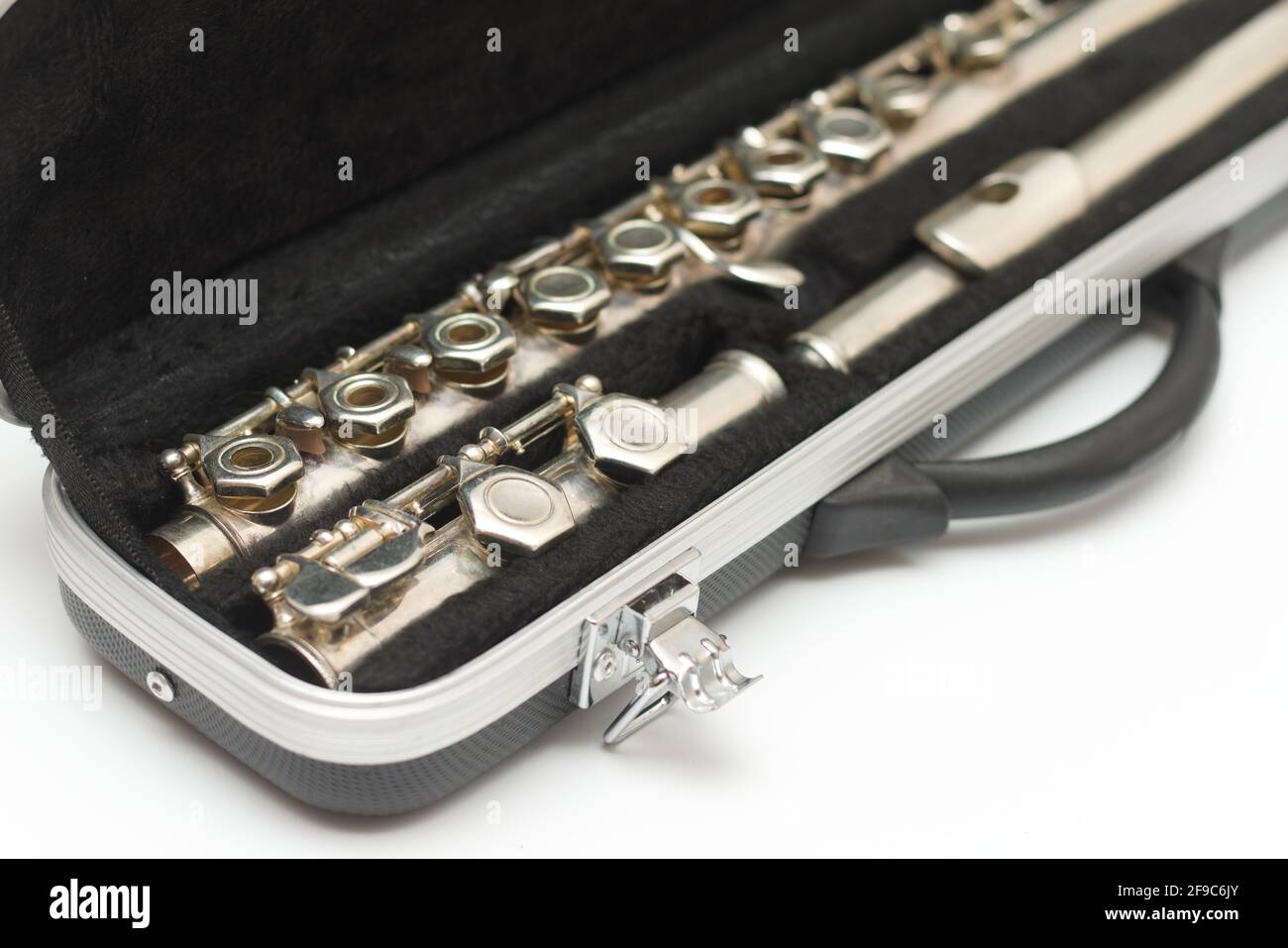 Partial side view of shiny disassembled silver flute in black case ...