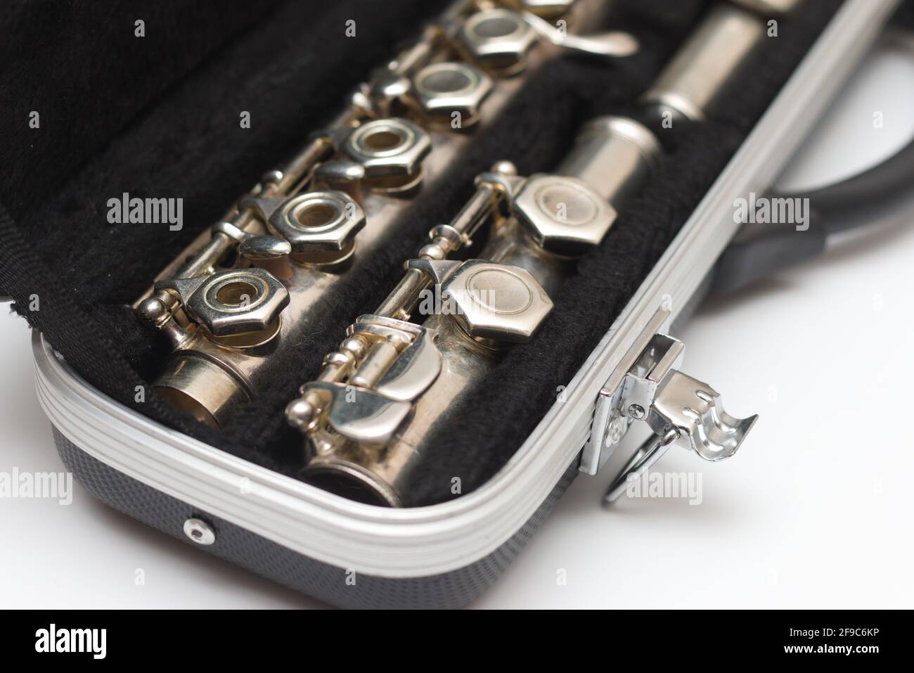 Side view of an open case with a flute lying in it with large keys ...