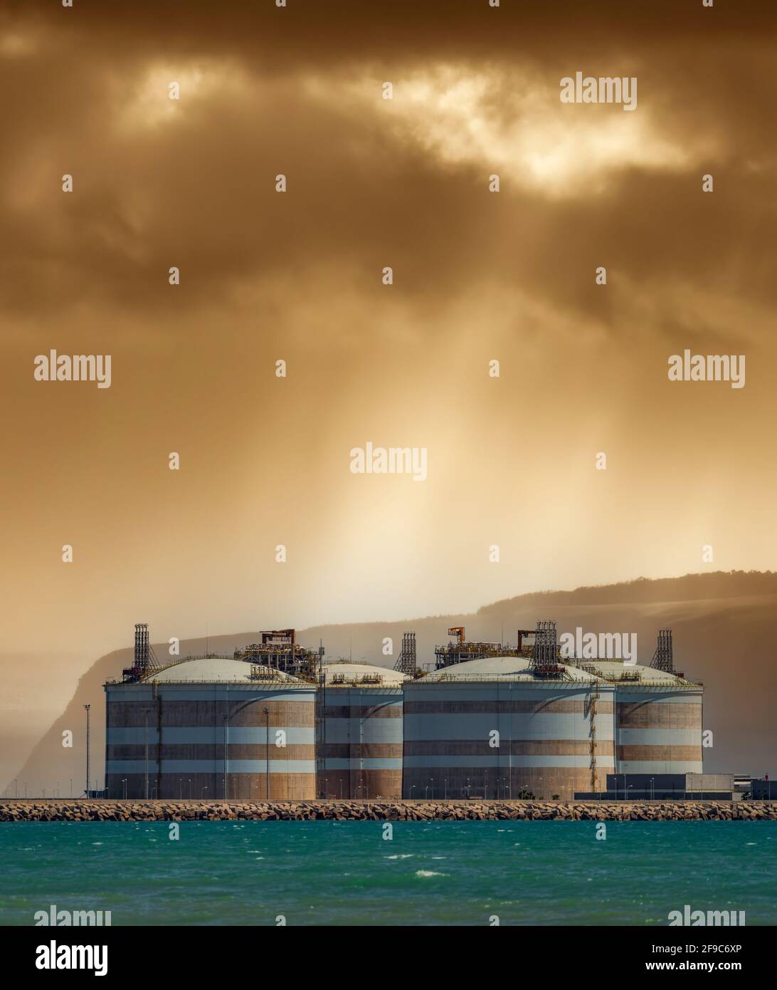 Huge tanks under orange ray lights in the background Stock Photo - Alamy