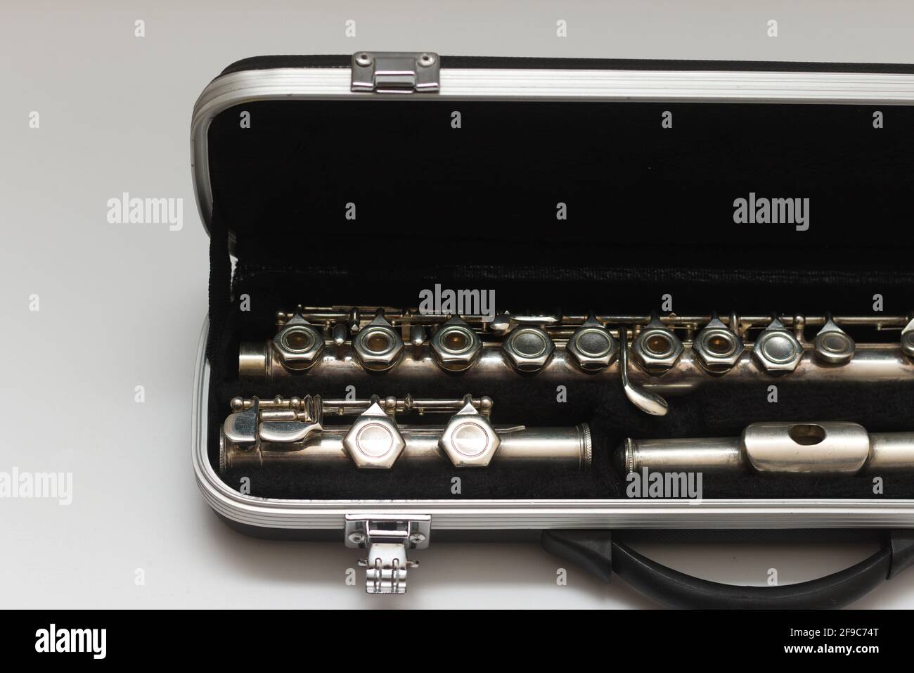 Partial view of a shiny disassembled silver flute in a black case ...
