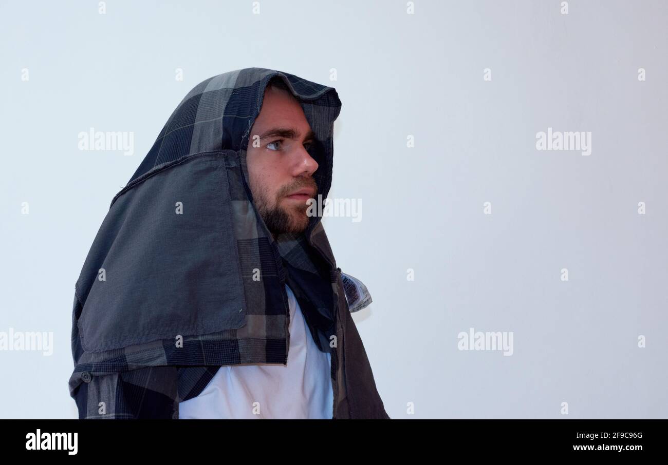 Side profile of a confused looking man with a shirt on his head ...