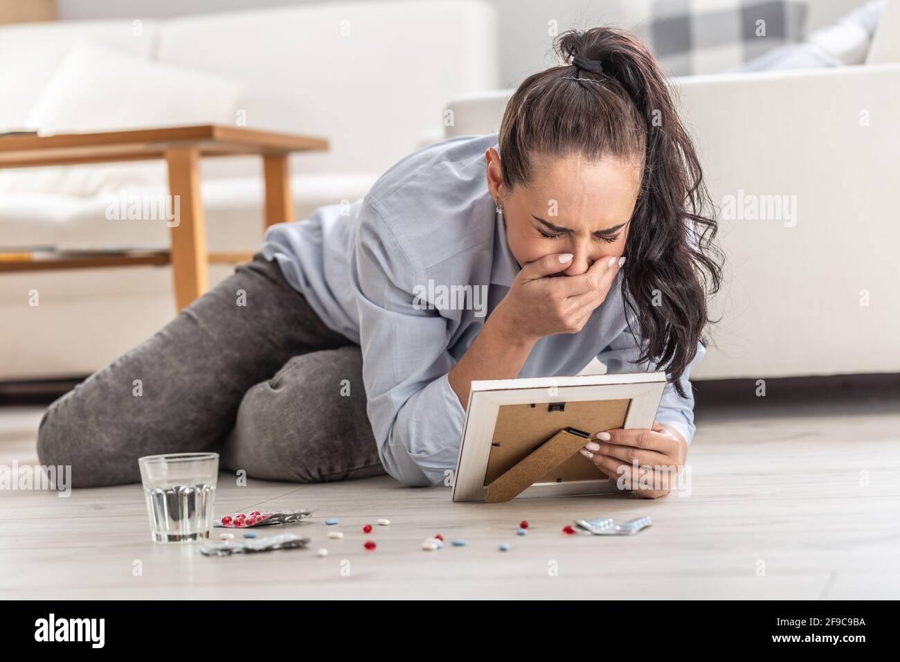 Woman considering drug overdose suicide crying over a picture of ...