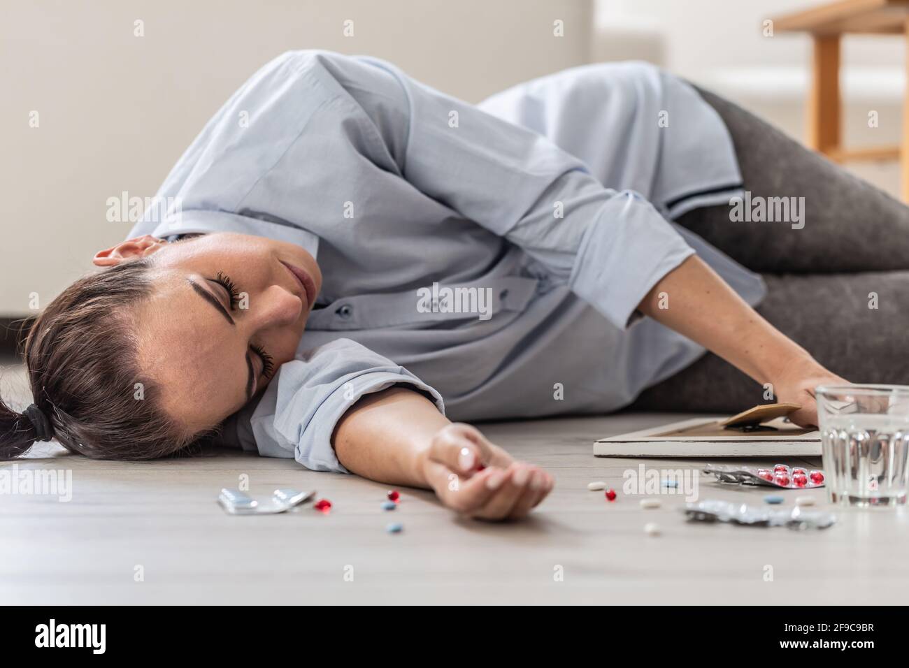 Young woman who overdosed on drugs lying on the floor fainted, holding ...