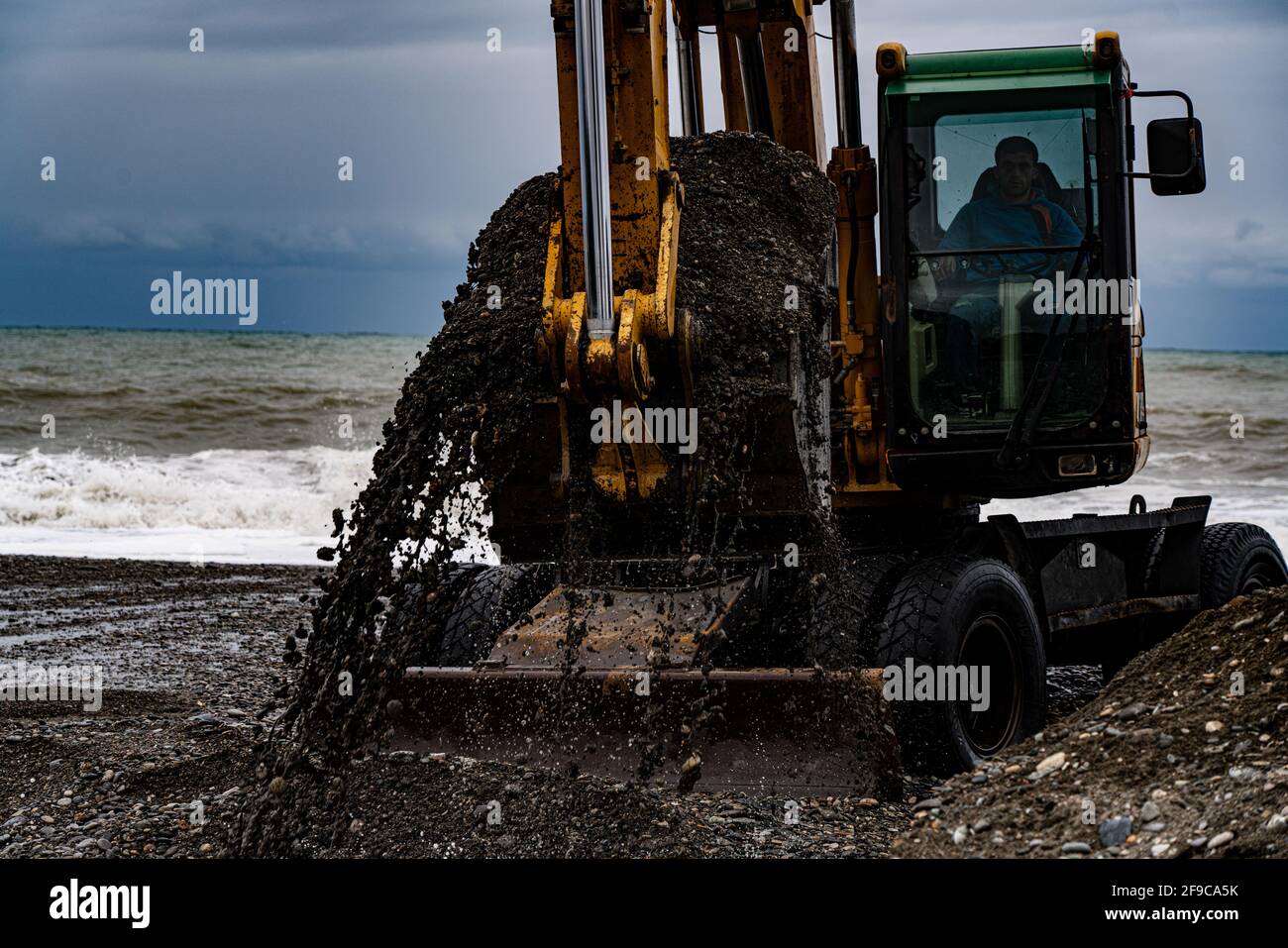 excavator works on the seashore in a storm Stock Photo - Alamy