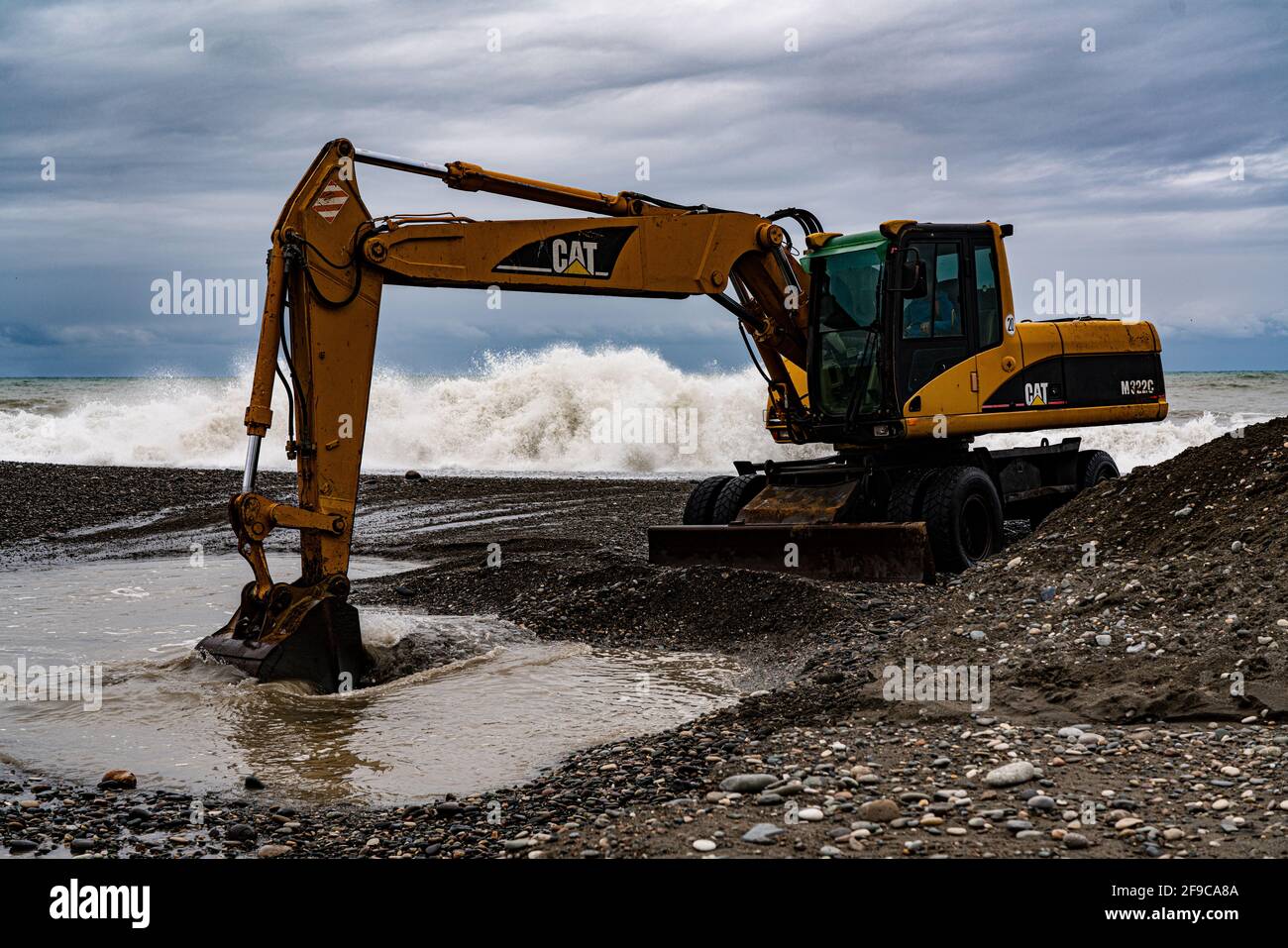 excavator works on the seashore in a storm Stock Photo - Alamy