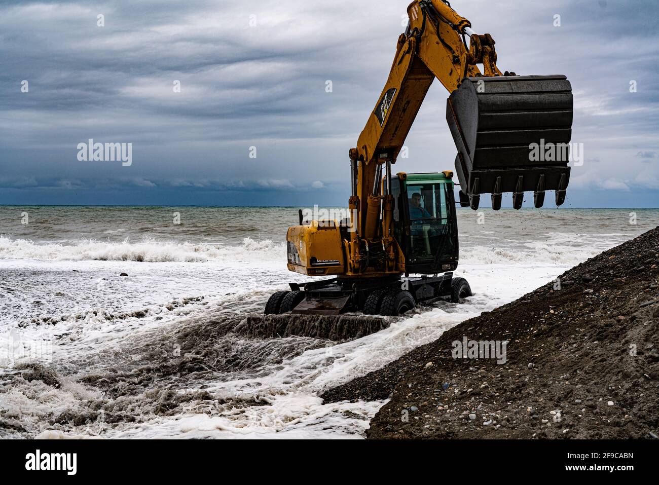 excavator works on the seashore in a storm Stock Photo - Alamy