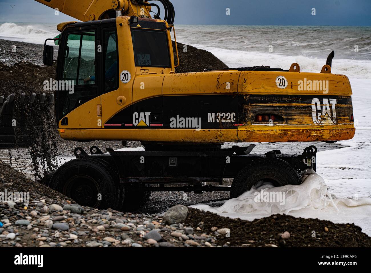 yellow excavator digging the seashore Stock Photo - Alamy