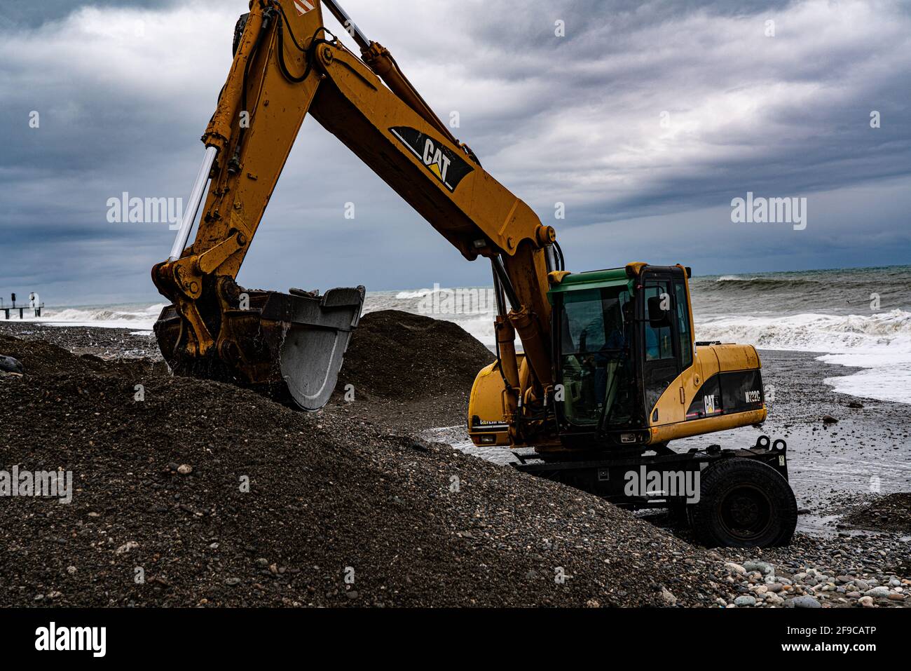 yellow excavator digging the seashore Stock Photo - Alamy