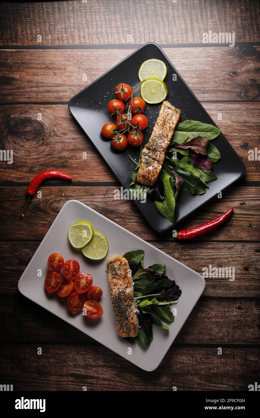 Top view of two salmon fillet plates with spinach, lemon, and cherry ...