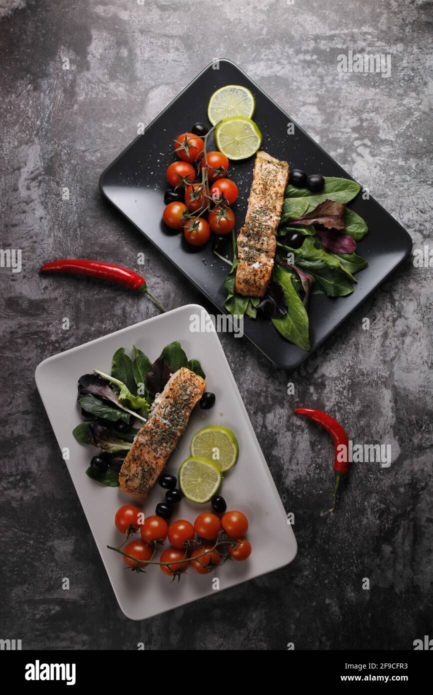 Top view of two salmon fillet plates with spinach, lemon, and cherry ...