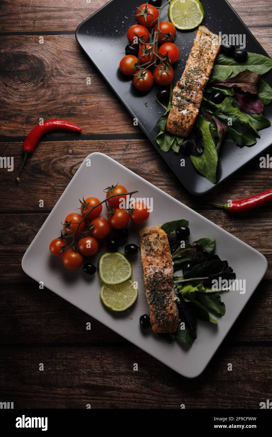 Top view of two salmon fillet plates with spinach, lemon, and cherry ...