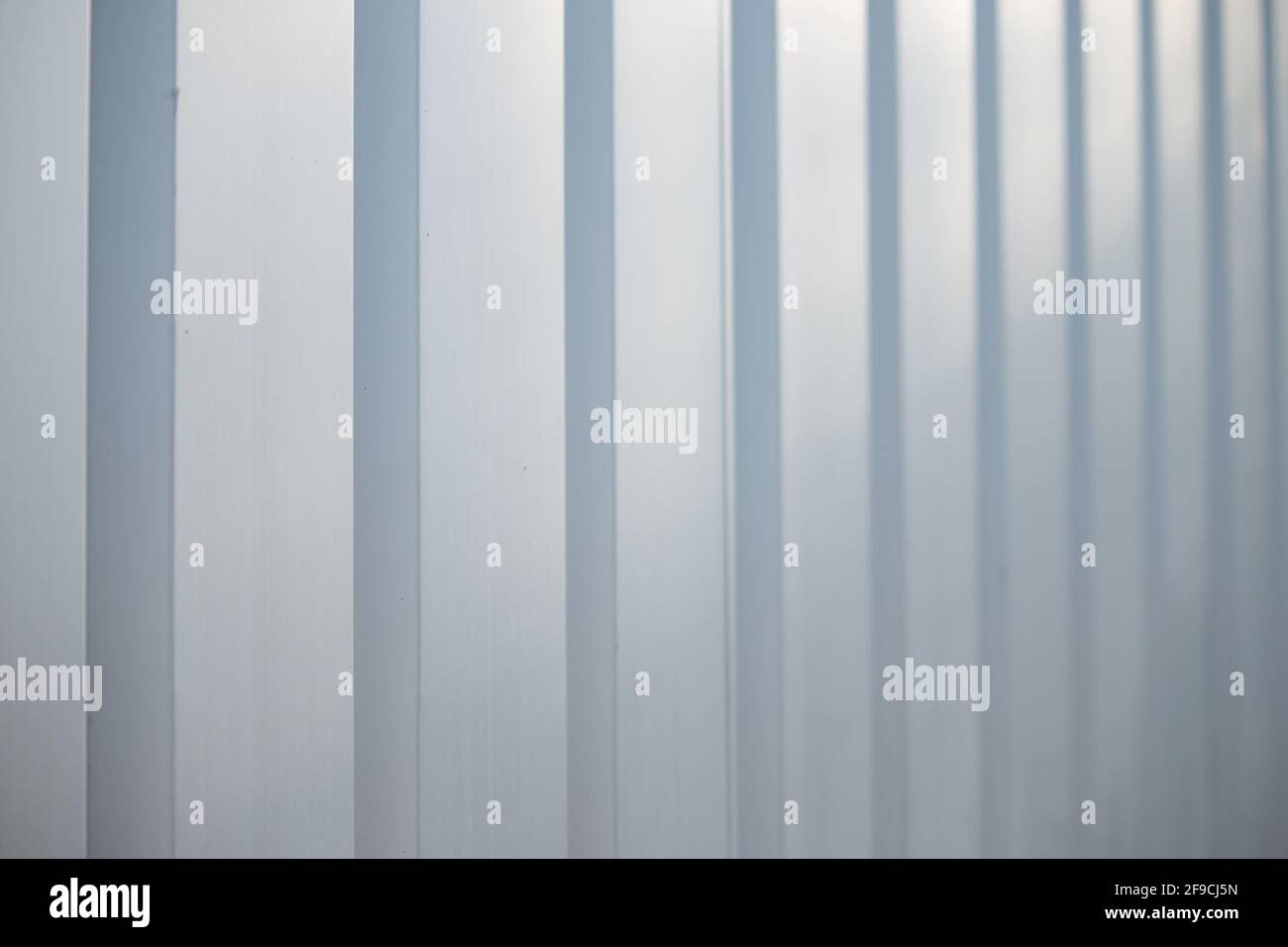 Shining reflective gray-blue metal panel striped wall receding into the ...