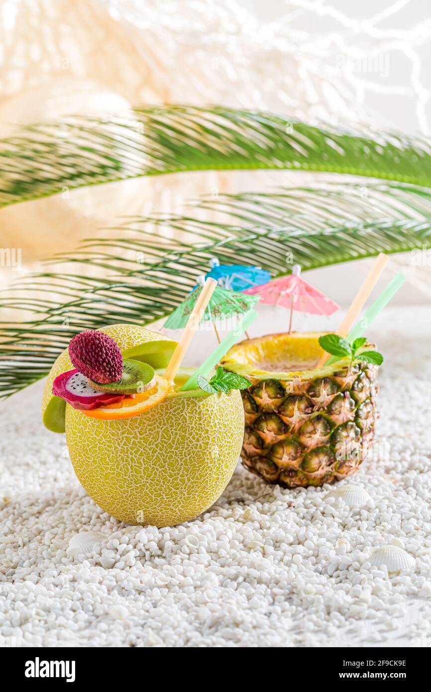 Tropical drinks in fresh melon and pineapple on white pebbles. Drink ...