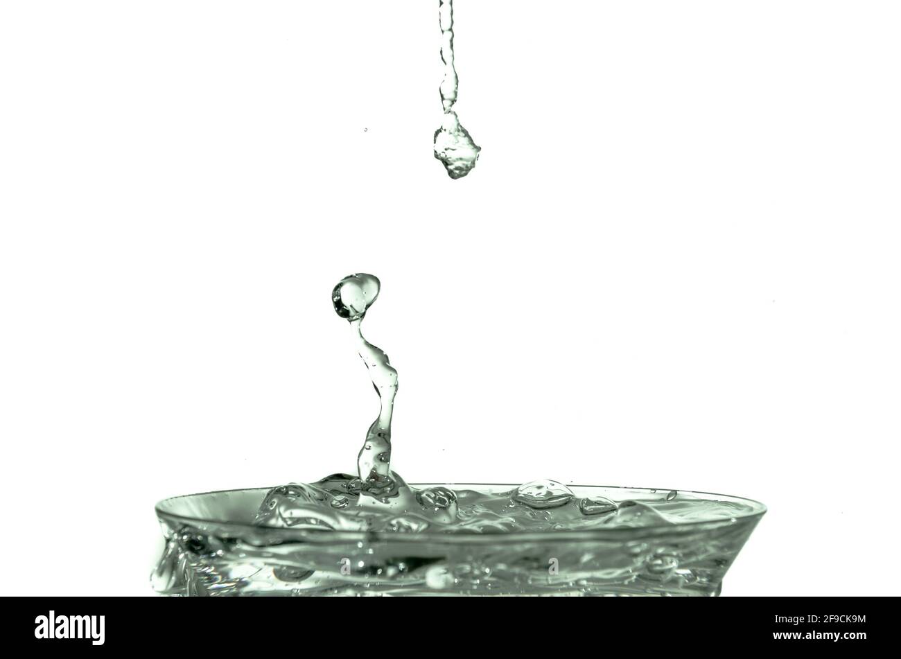 Closeup of water drops falling into a glass isolated on white ...